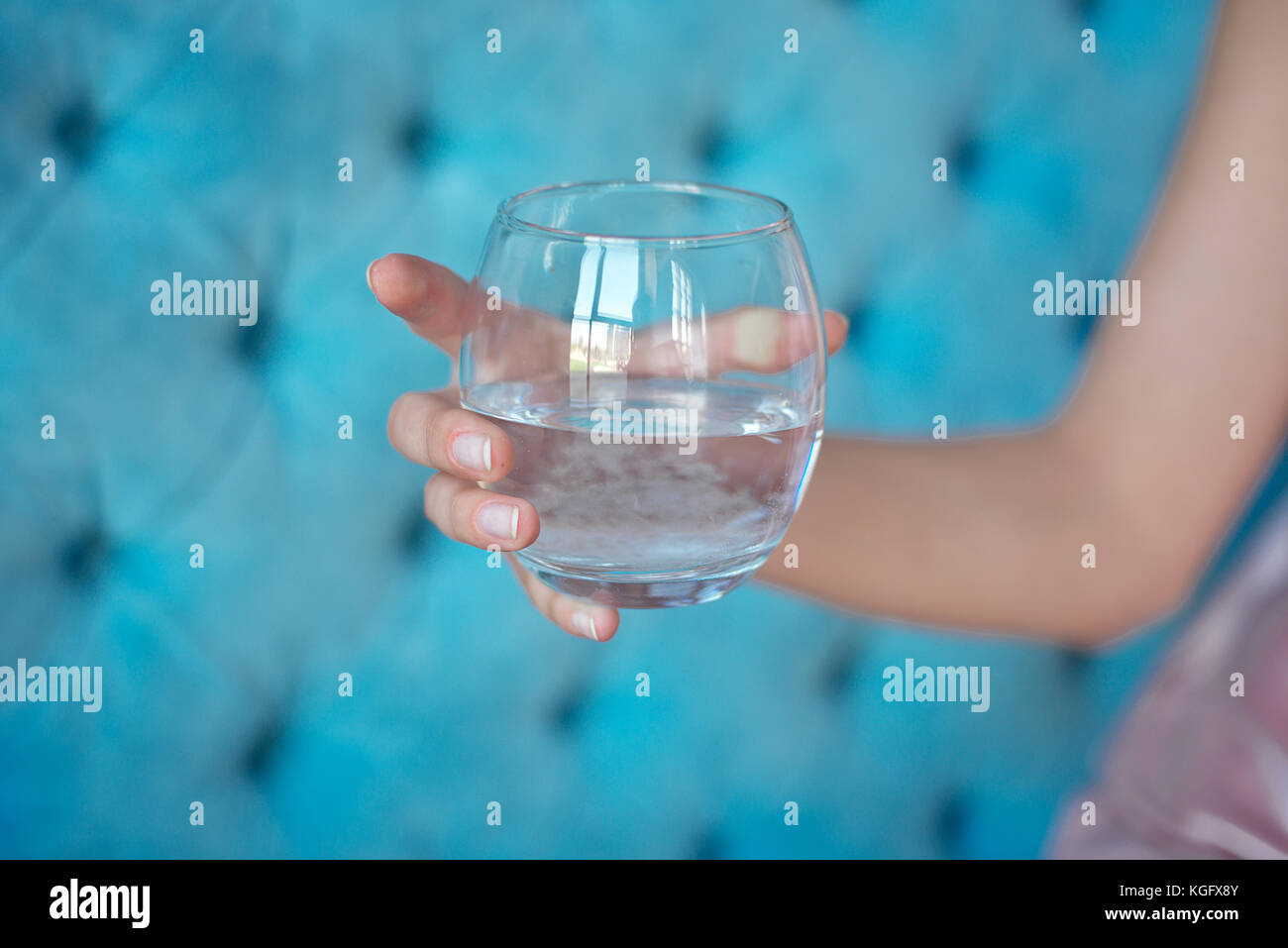 Female hands holding a clear glass of water. Slime body on background ...