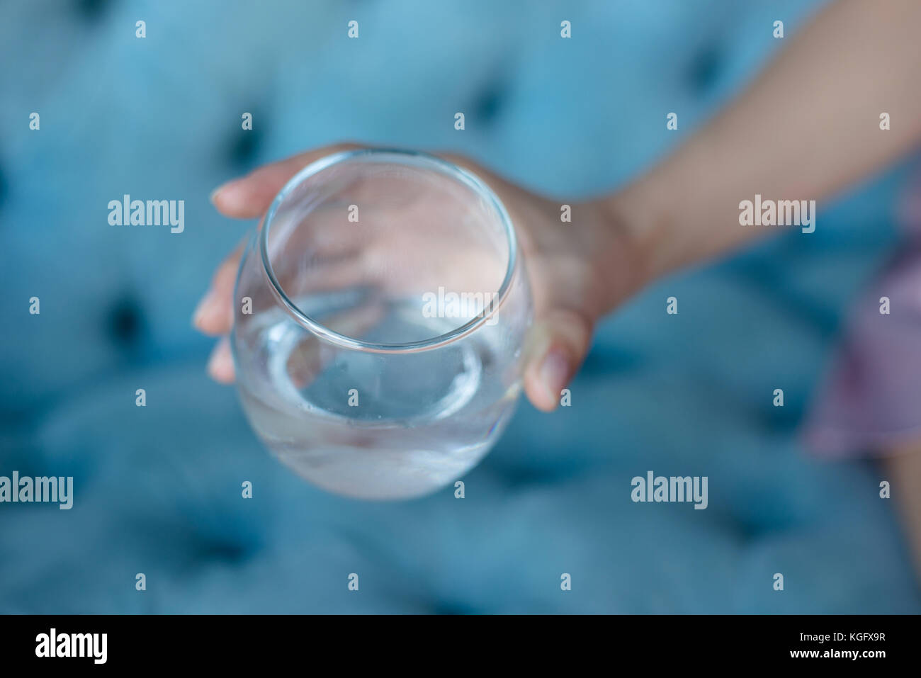 Female hands holding a clear glass of water. Slime body on background ...