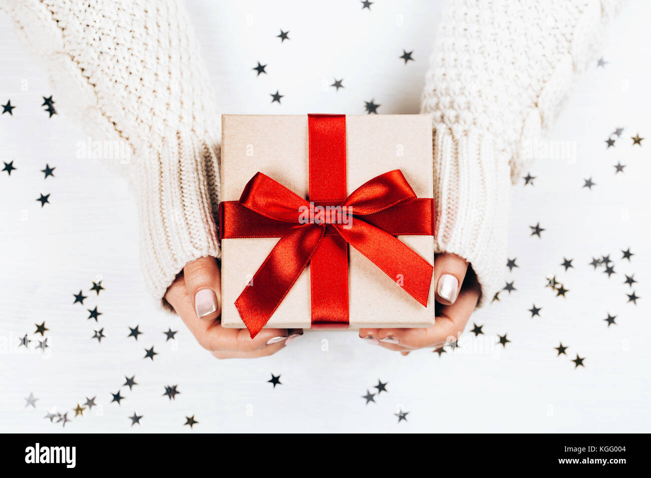 Female hands holding present with red bow Stock Photo - Alamy