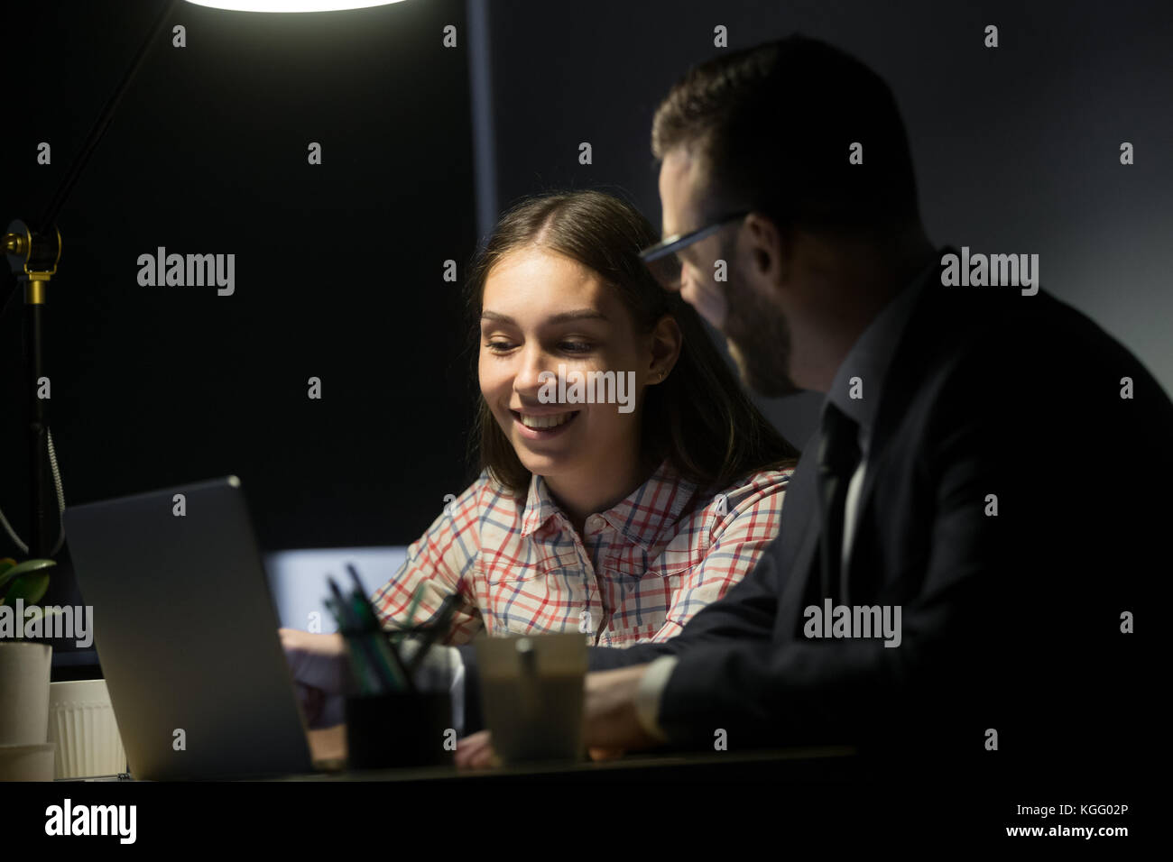 Two happy smiling colleagues working on project using laptop computer ...