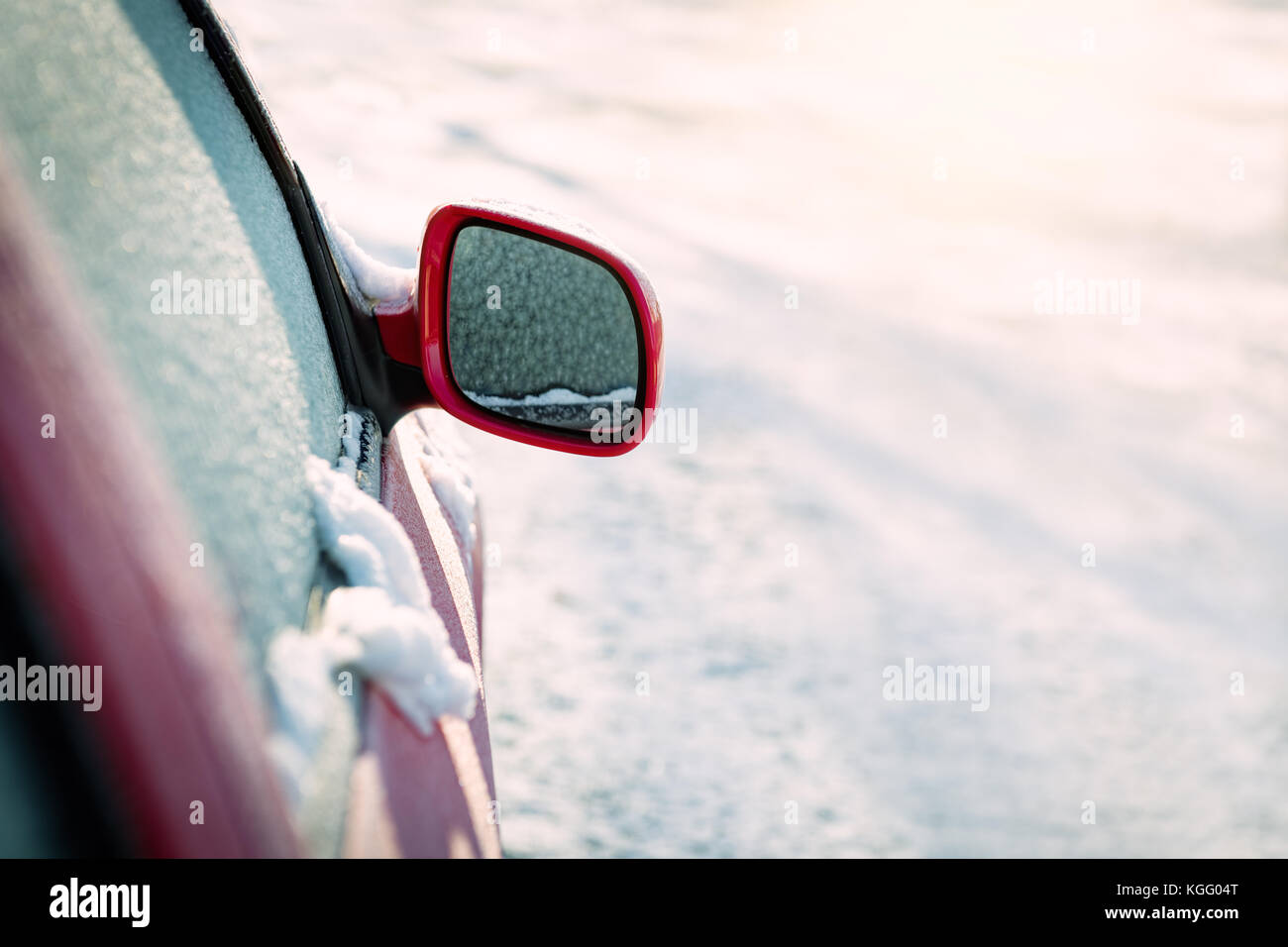 Frozen red car parked outside, with focus on rear view mirror, winter ...