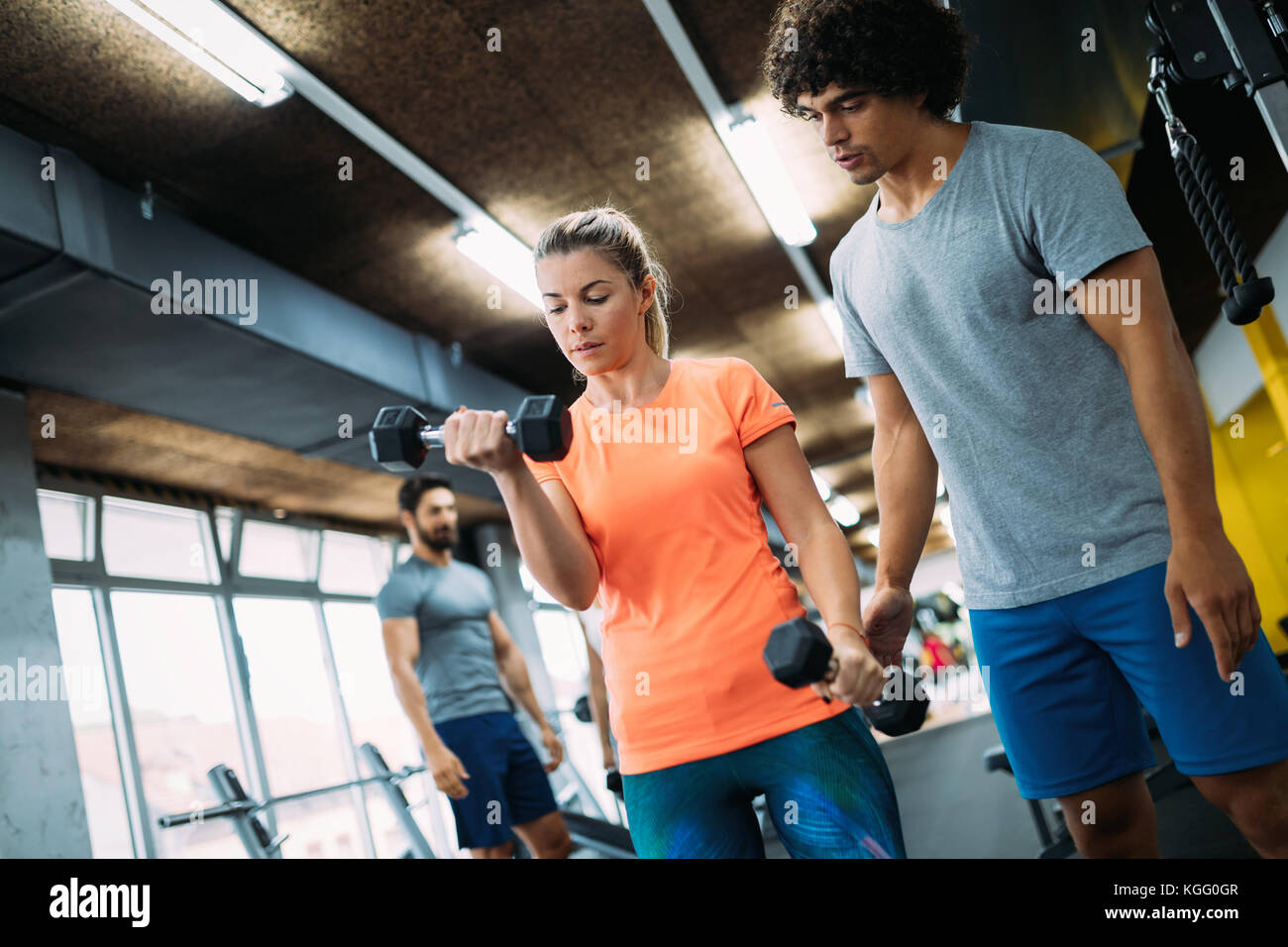 Young beautiful woman doing exercises with personal trainer Stock Photo ...