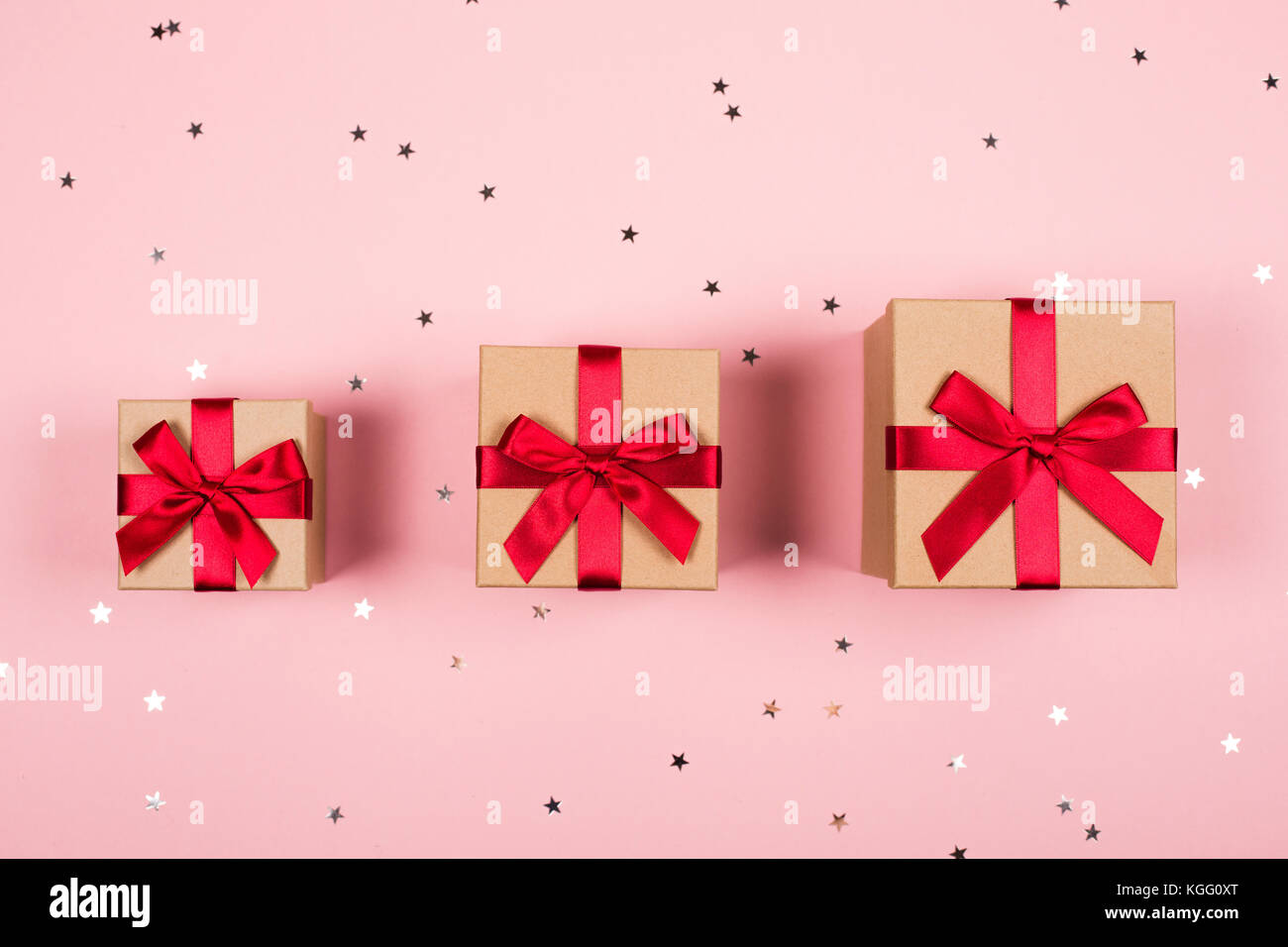 Three presents with red bow on pink Stock Photo - Alamy