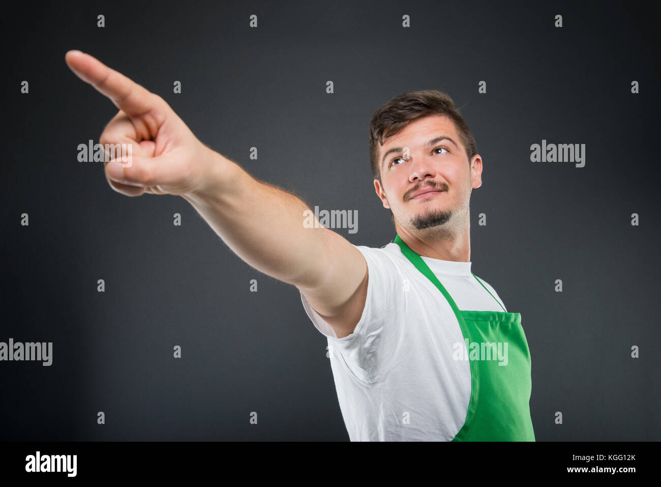 Low angle of male supermarket employer pointing up on black background ...