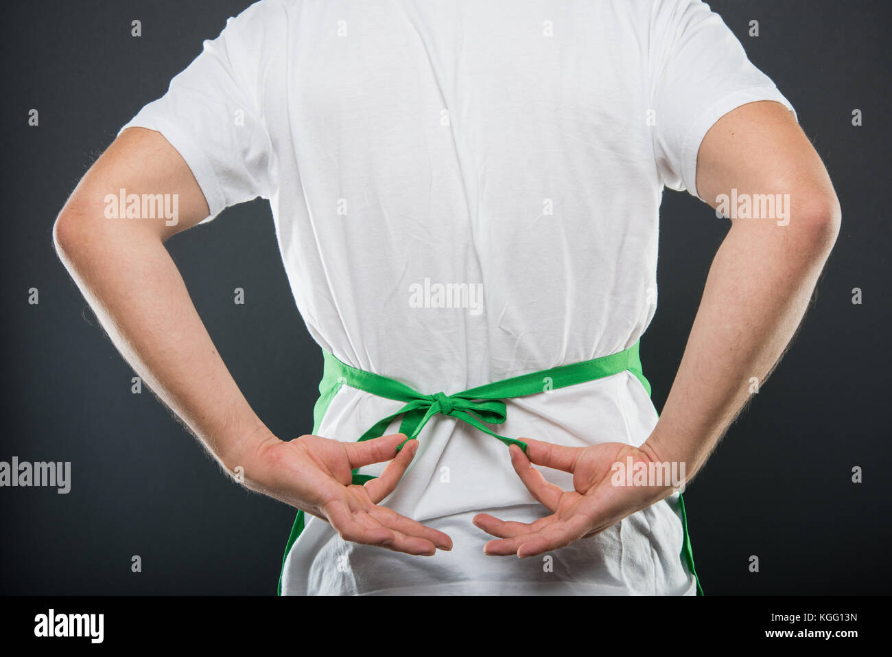 Back view of supermarket employer tying the apron on black background ...