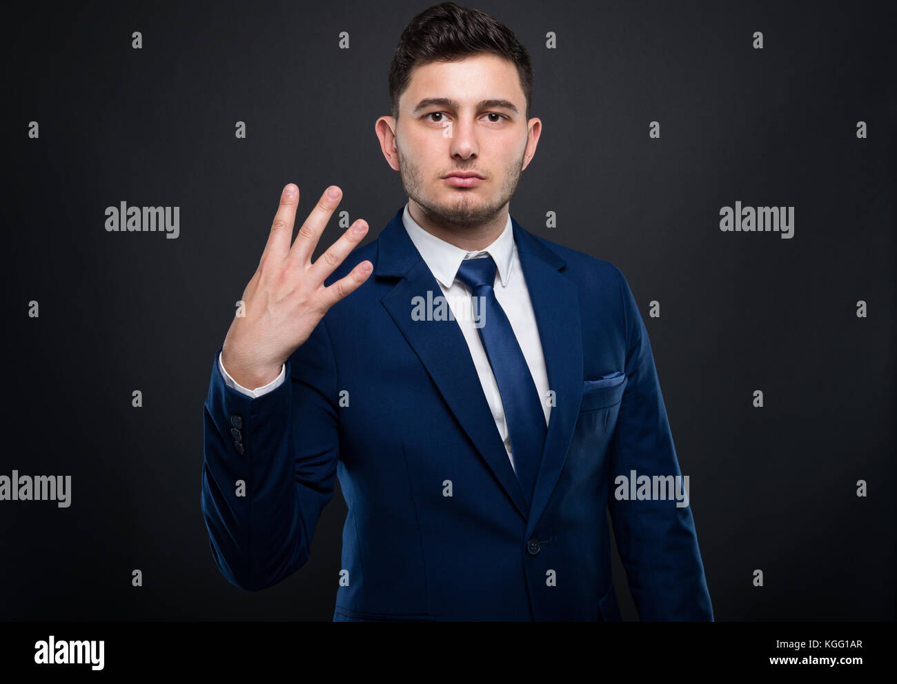 Businessman pointing up number number four with his fingers on dark ...