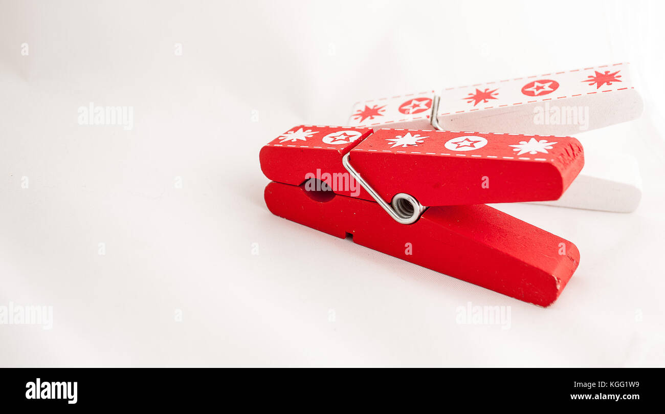 White and red wooden decorated pegs on a white background in studio ...