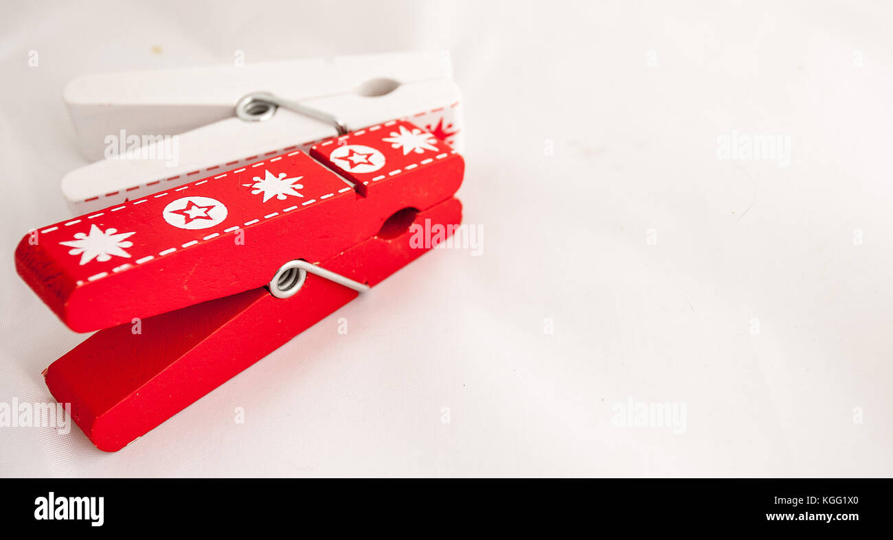 White and red wooden decorated pegs on a white background in studio ...