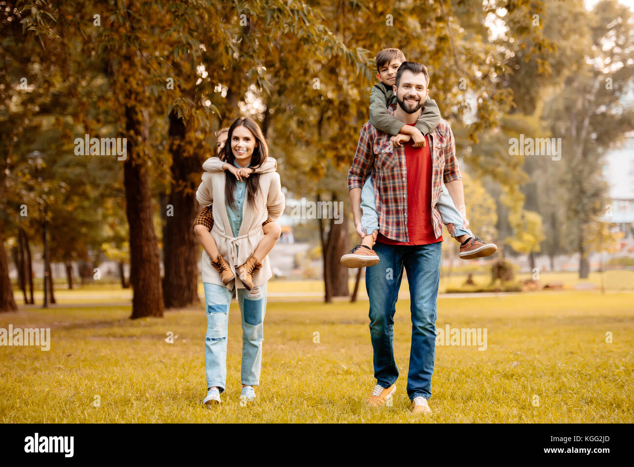 Parents giving children piggyback ride Stock Photo - Alamy