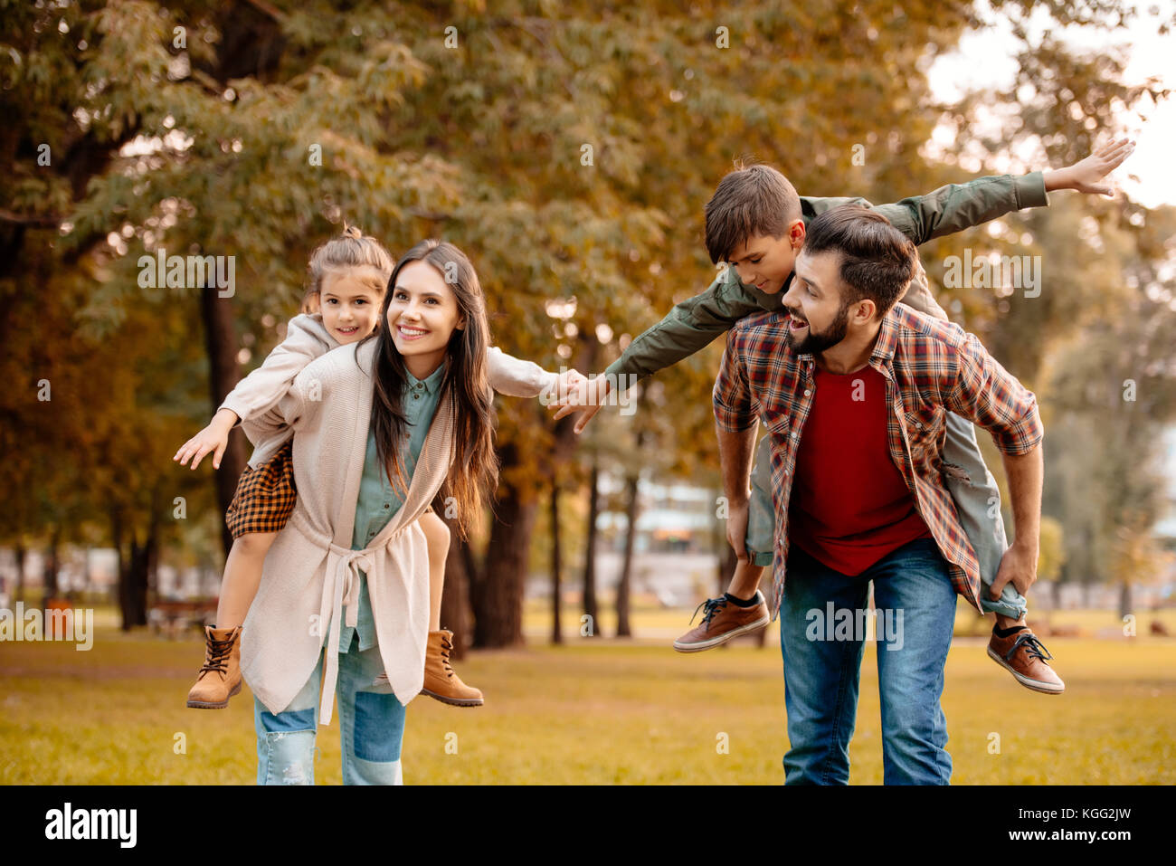 Parents giving children piggyback ride Stock Photo - Alamy
