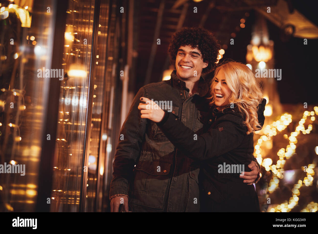 Couple having fun outdoors at Christmas time pointing at something ...