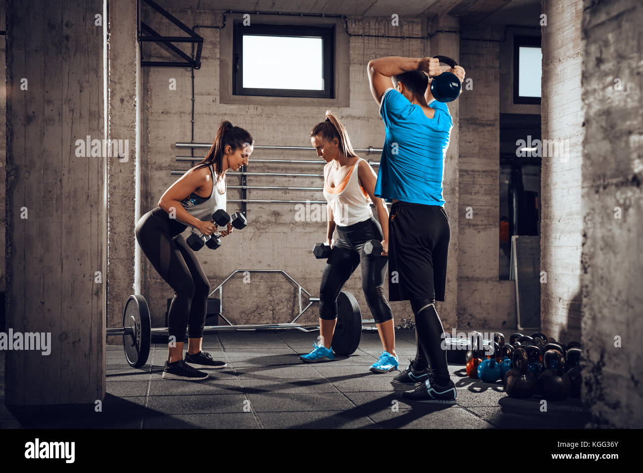 Three young friends doing exercise for biceps and triceps at the gym ...