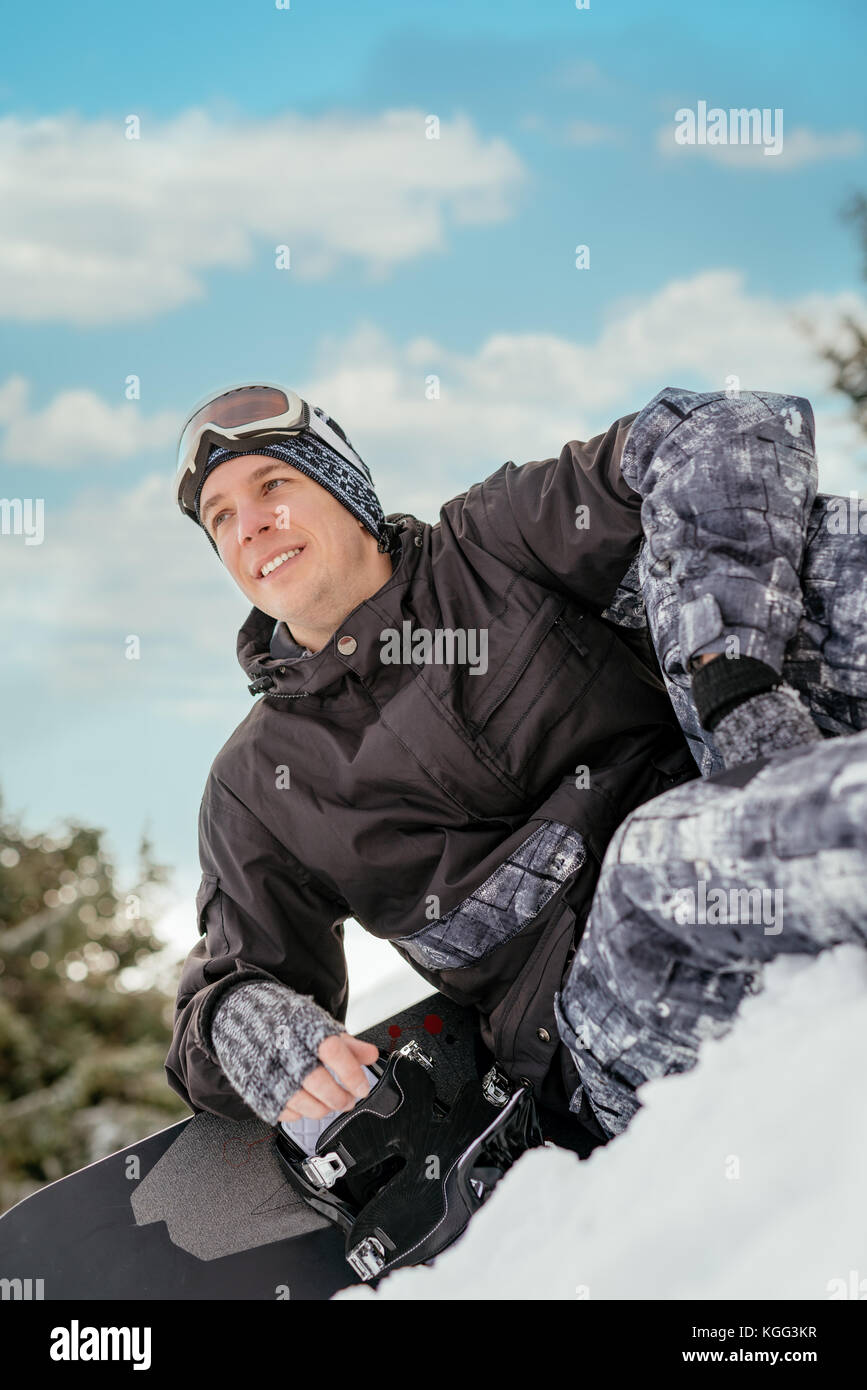 Beautiful young smiling man with snowboard enjoying a sunny winter day ...
