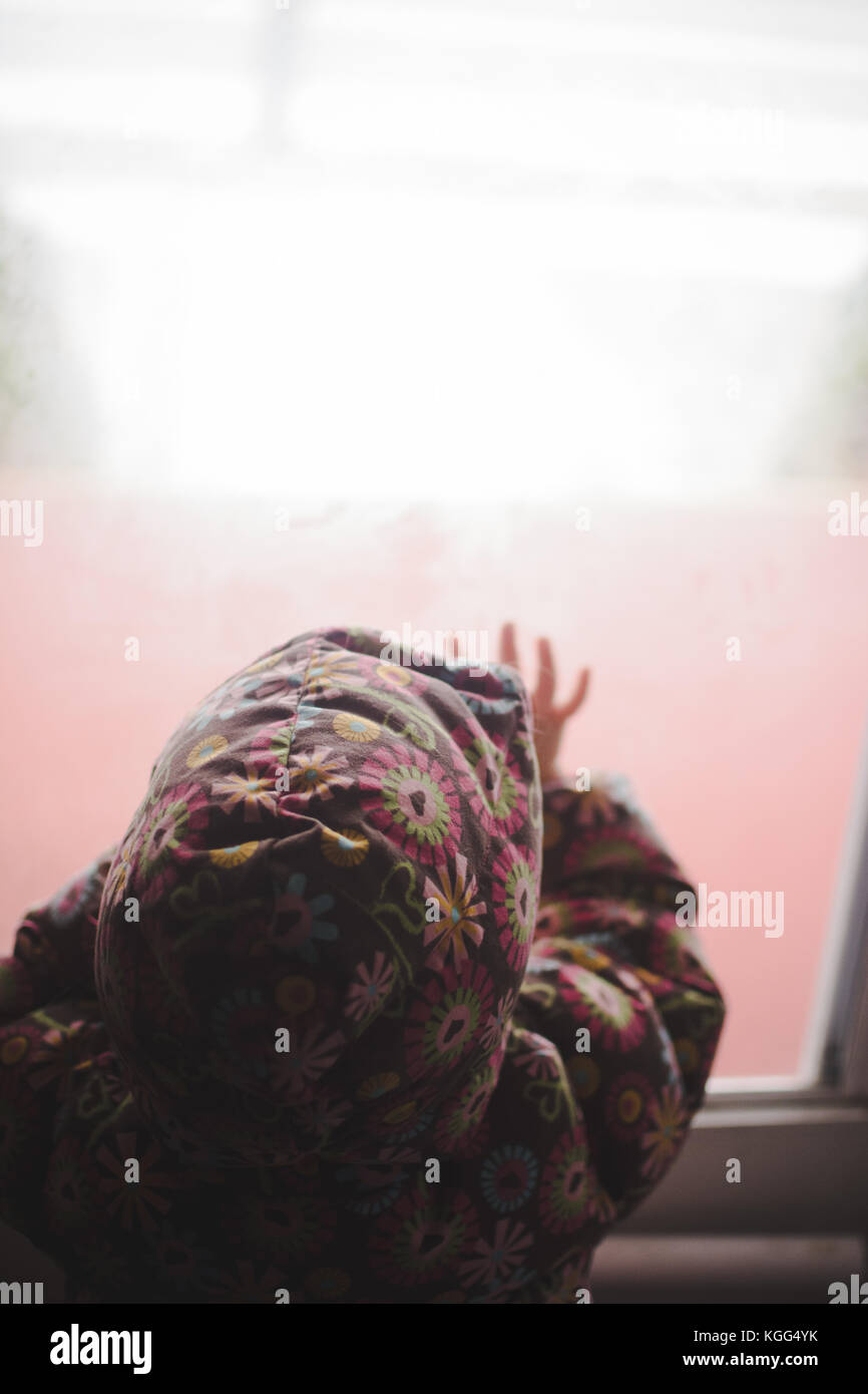 A little girl looks out a window at cold weather Stock Photo - Alamy