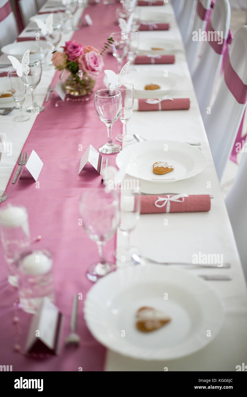 Pink and white wedding table with pink runner, empty wine glasses ...