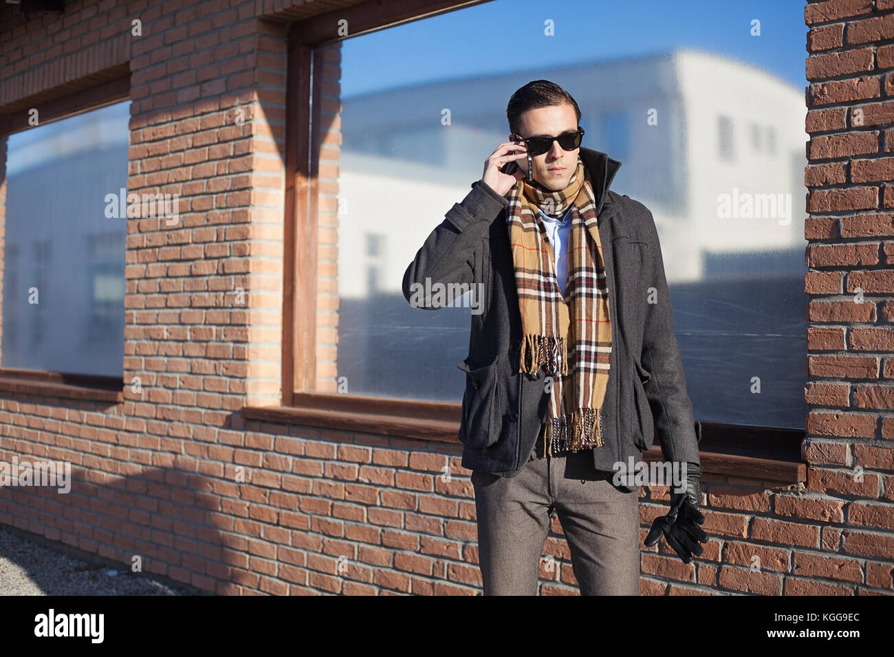 man in a winter jacket with serious face talking on a cellphone ...