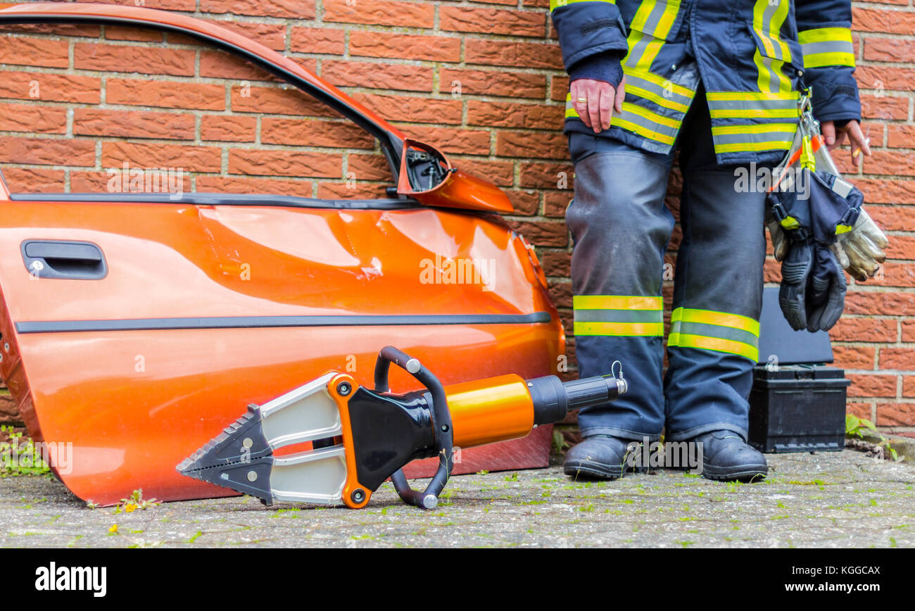 german firefighter stands near a car door with an emergency tool Stock ...