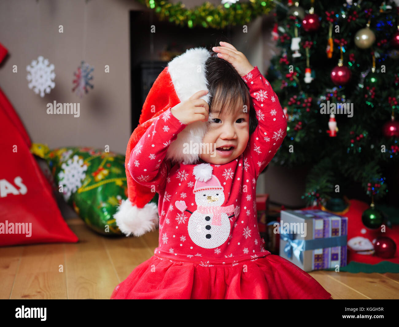 baby girl taking santa hat off Stock Photo - Alamy