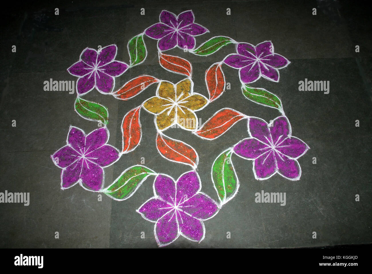 Creation of flowers and leaves in Rangoli art using stone powder mixed ...