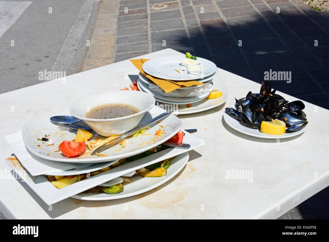 Dirty plates stacked on a restaurant table ready to be washed along the ...