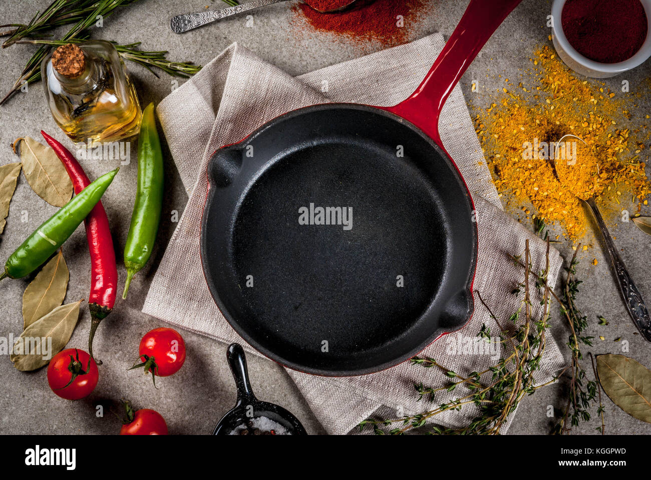 Grey stone culinary background with empty black pan and selection of ...