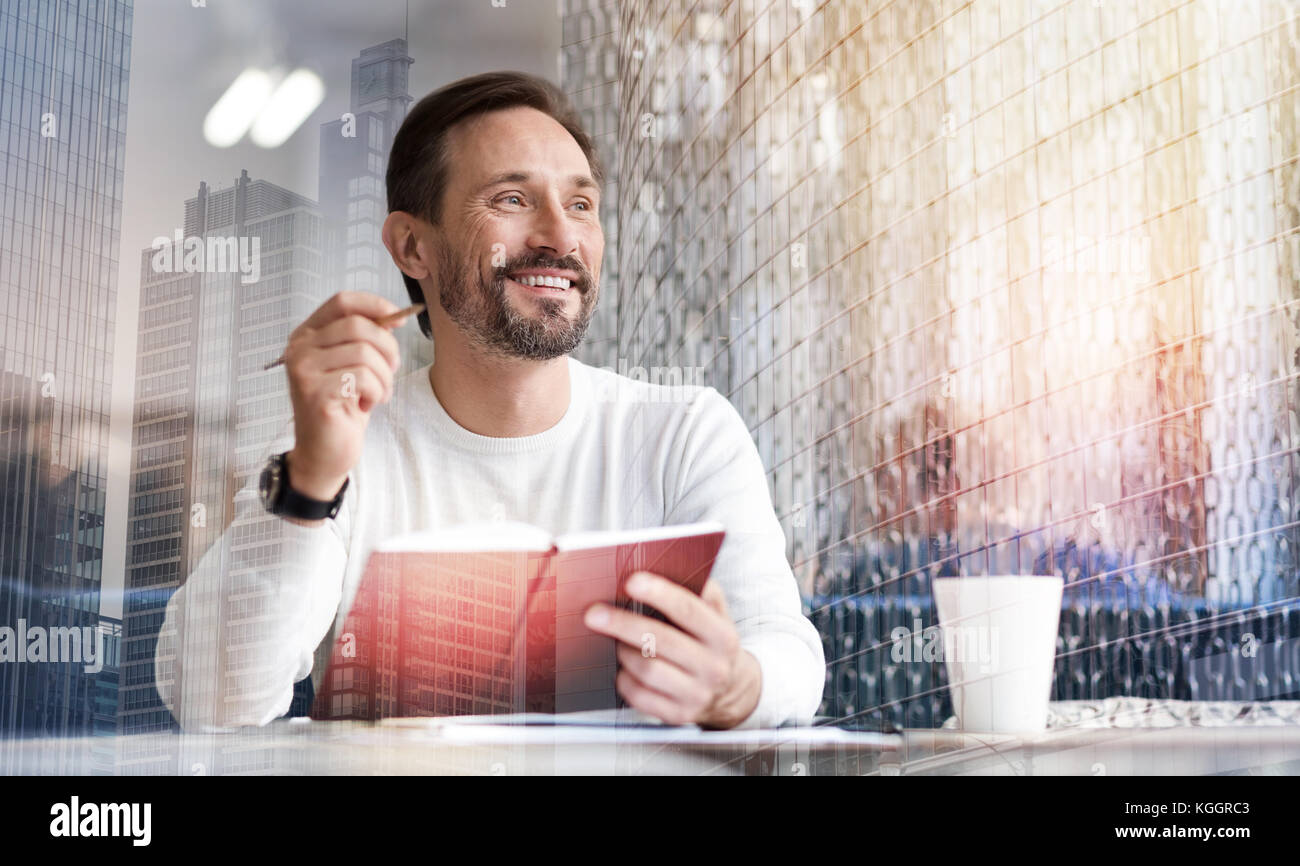 Smiling man looking for inspiration while writing poems Stock Photo - Alamy