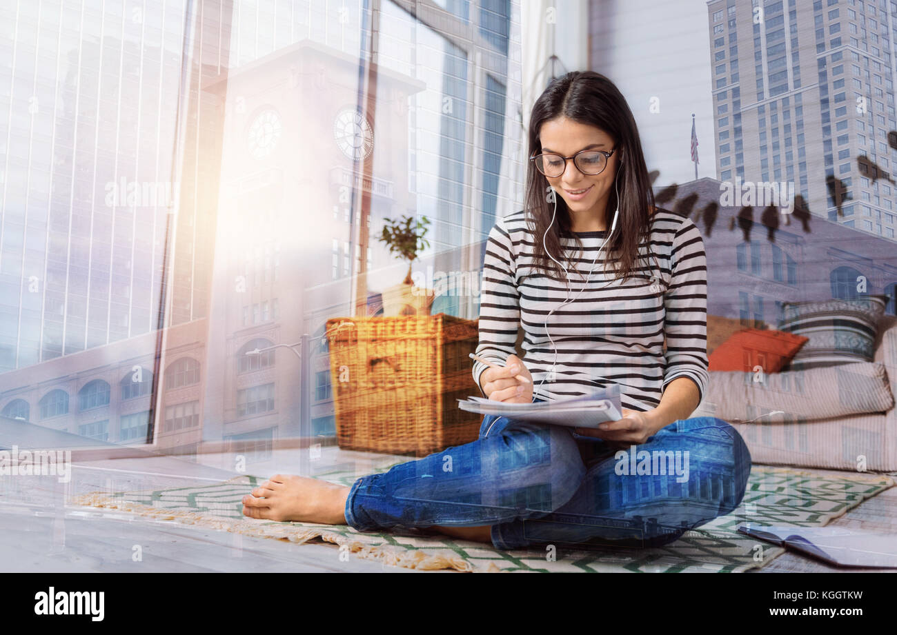 Pretty cheerful student listening to the music while doing homework ...