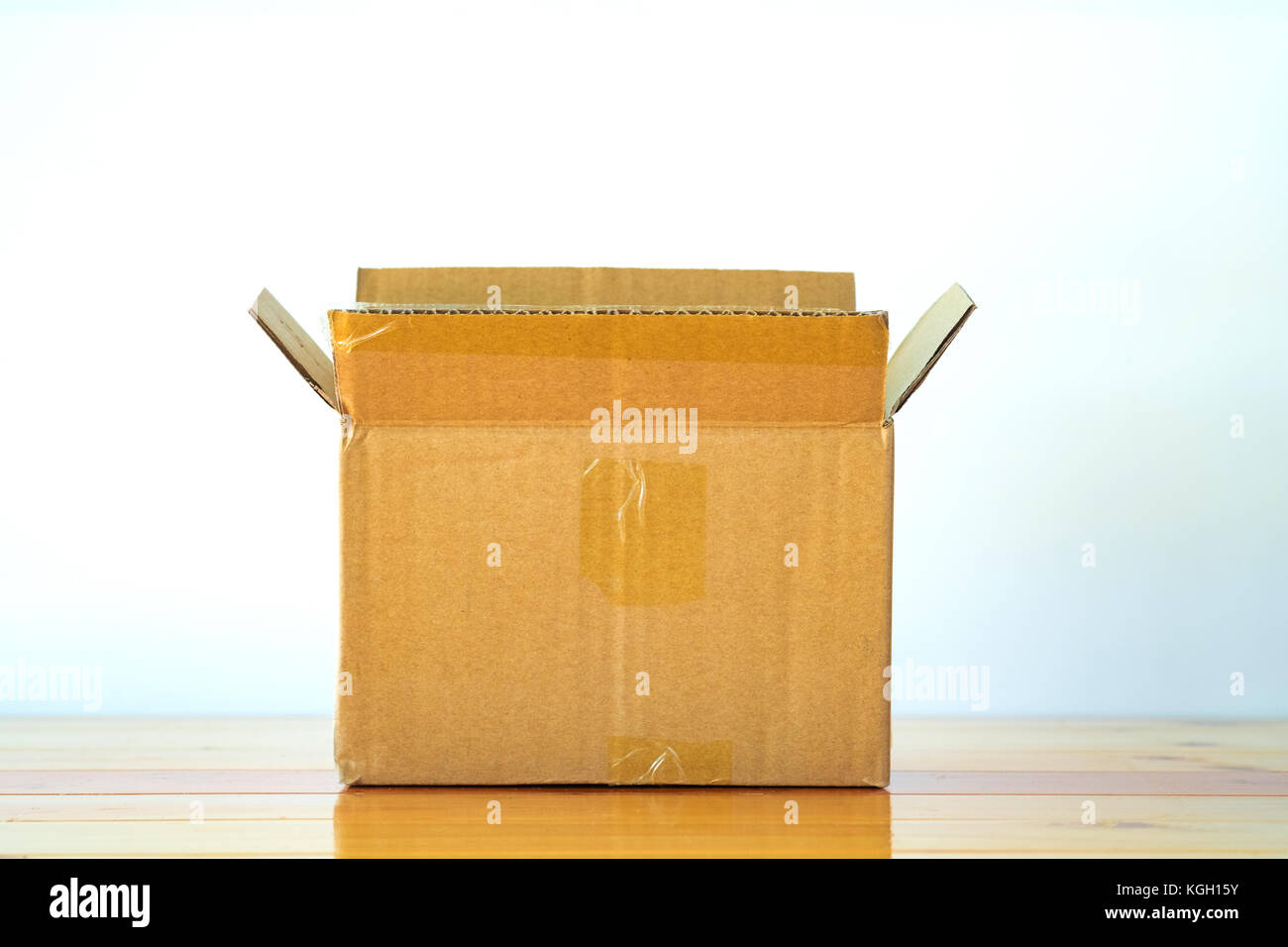 Empty opened old brown cardboard box for mock up on bright wooden table ...