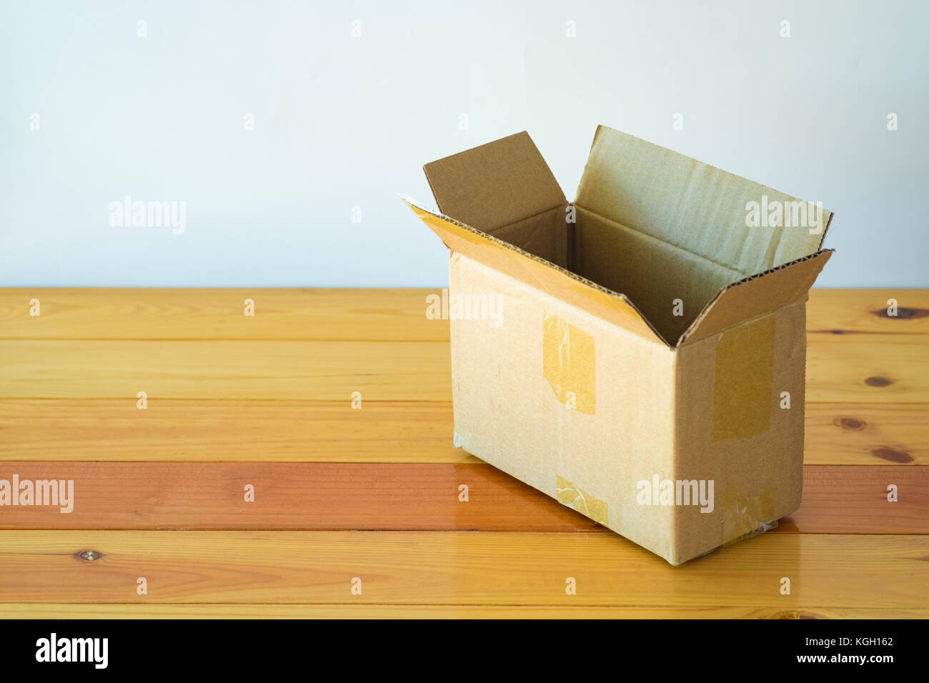 Empty opened old brown cardboard box for mock up on bright wooden table ...