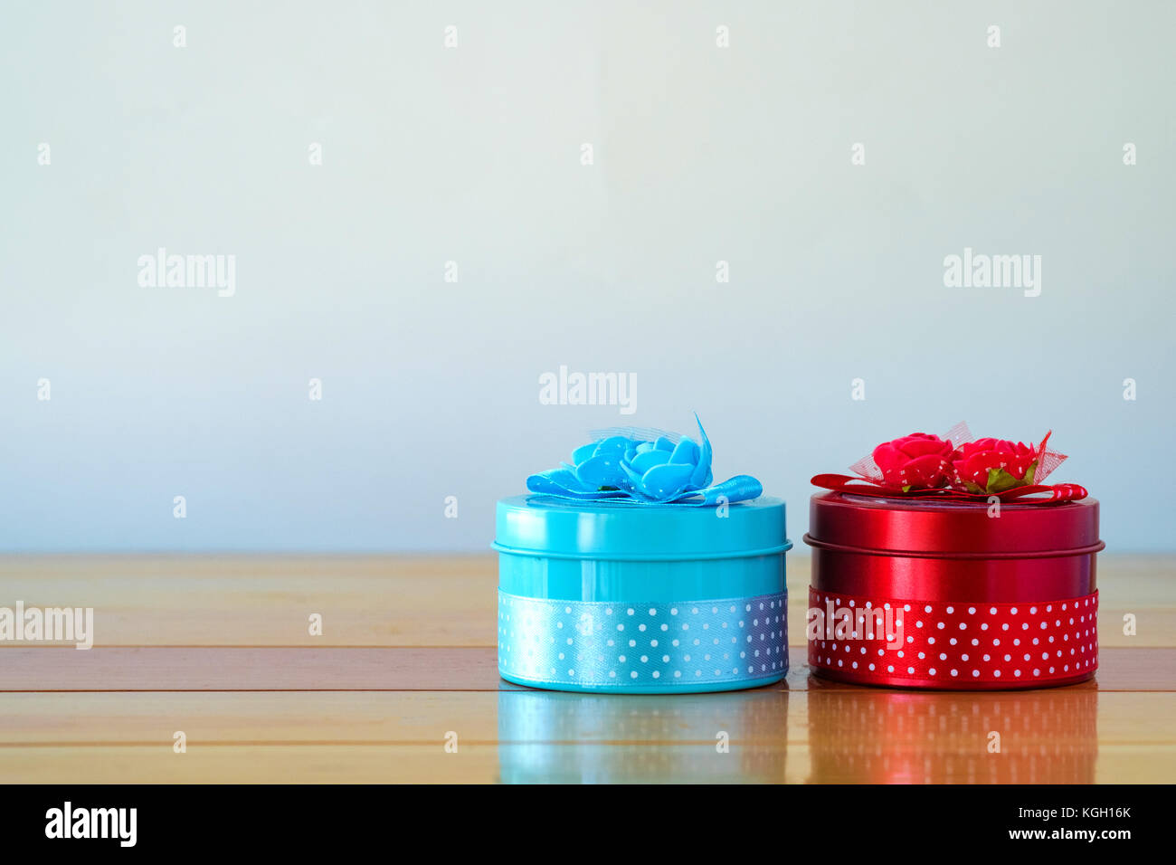 Round red and blue gift box with ribbon bow on bright wooden table with ...