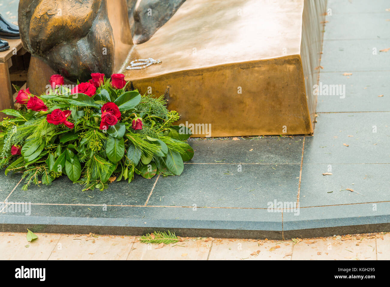 floral composition of roses at the foot of religious statue near a ...