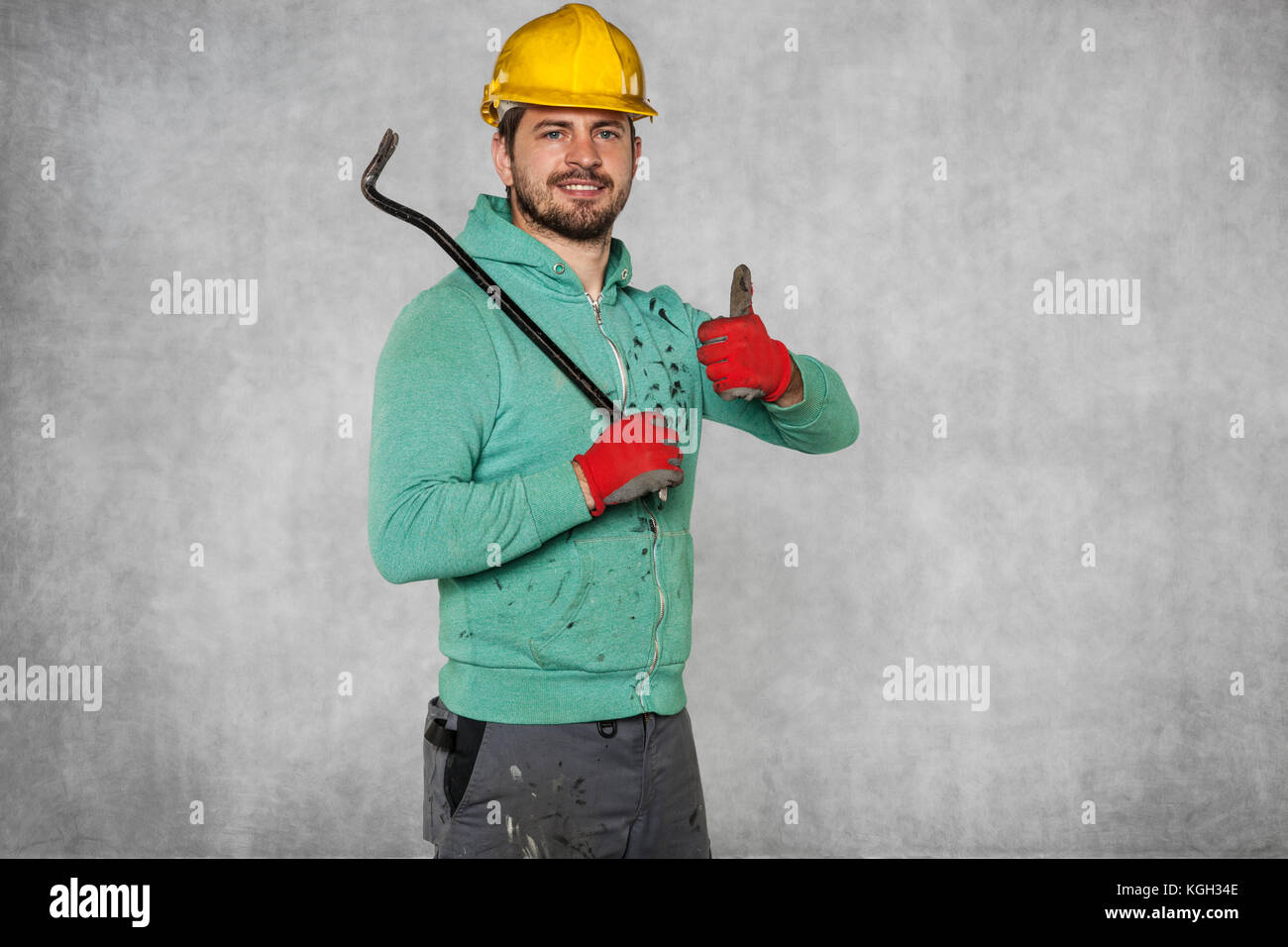 Worker holding a crowbar in his hand, thumb up Stock Photo - Alamy