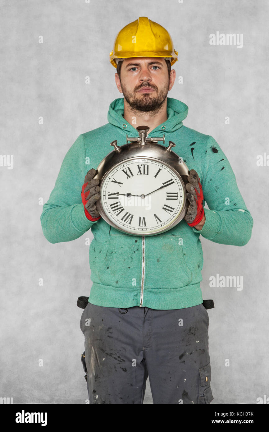 The concentrated worker keeps the clock in front of him Stock Photo - Alamy