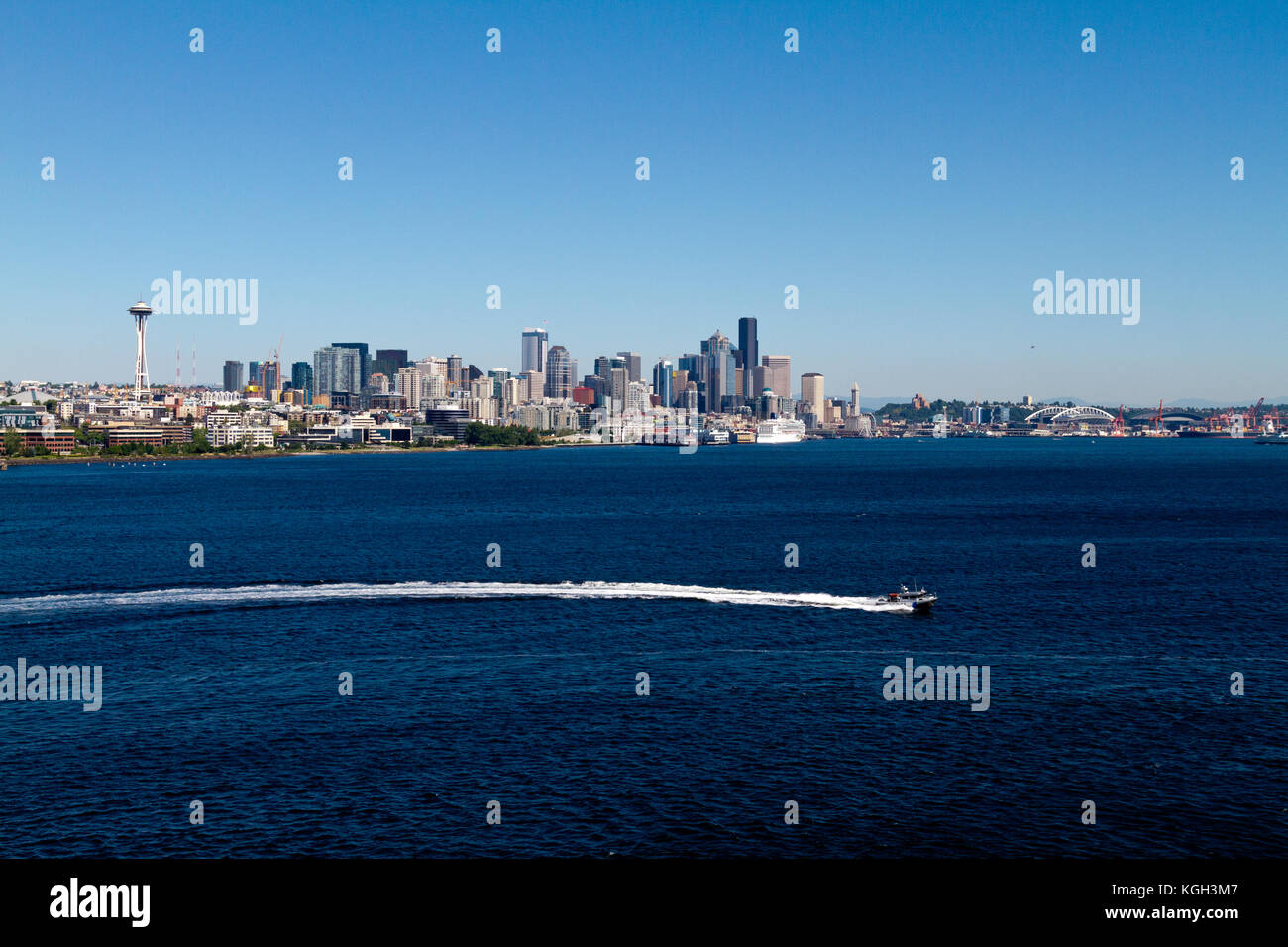 A powerboat speeding through the water with the skyline of Seattle in ...