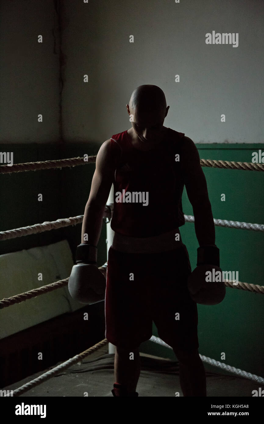 portrait of male boxer standing in the ring, looking down, focusing. He ...