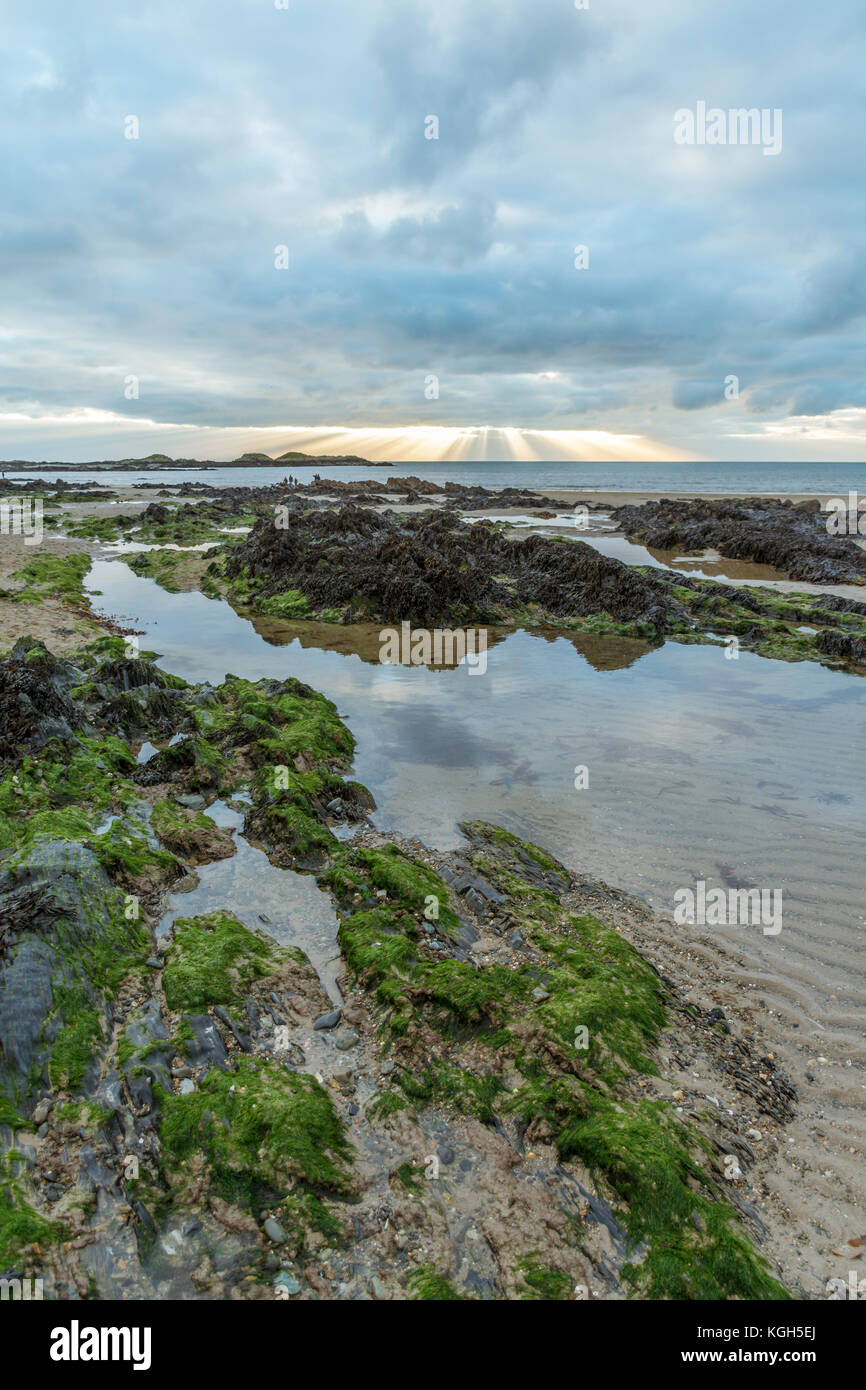 Sun beams on the horizon at the Town beach, Rhosneigr on Anglesey Stock ...