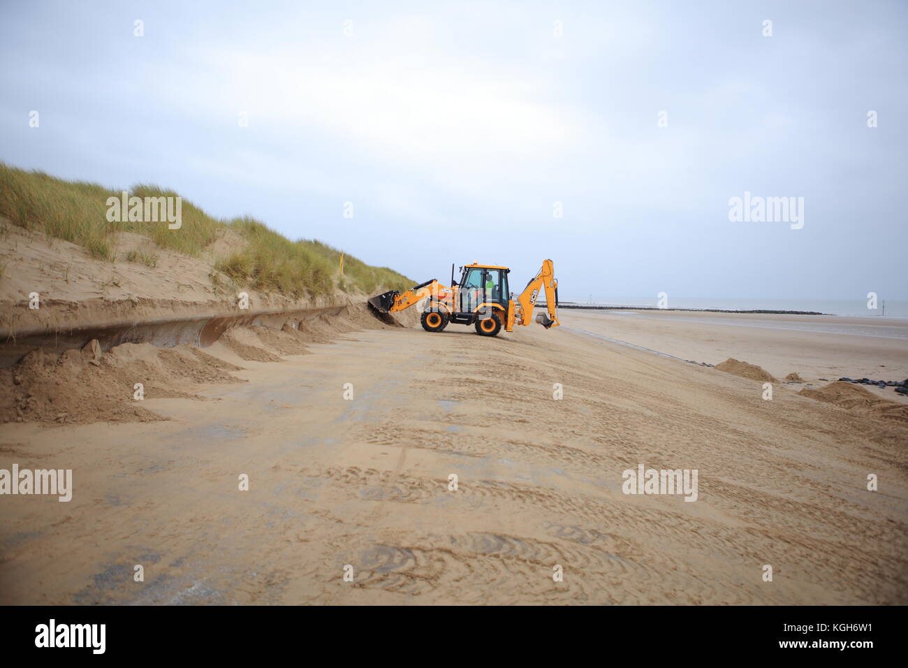 Digger moves sand on the beach at Prestatyn, North Wales for coastal ...