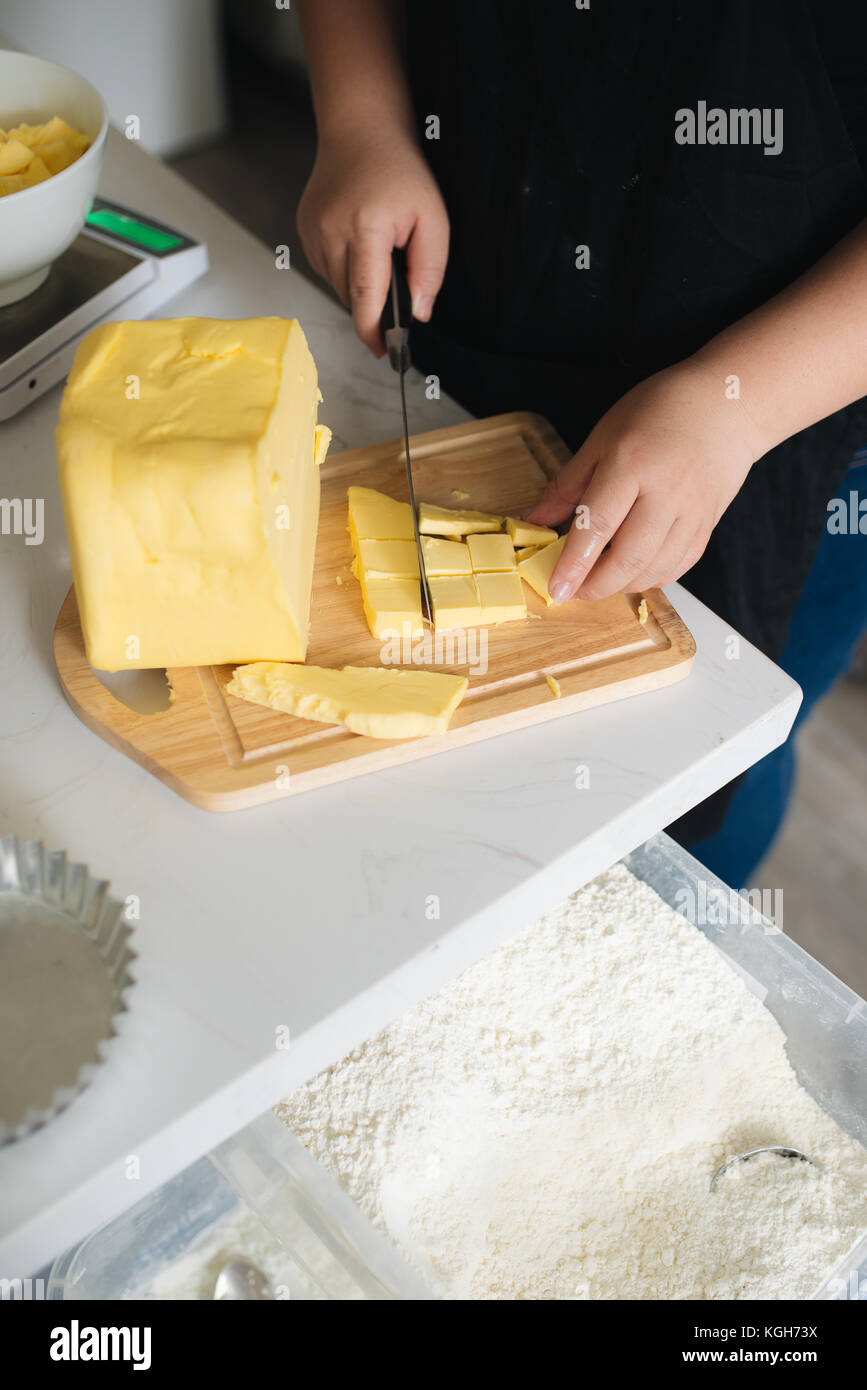 Cropped image of female chef cutting butter in kitchen Stock Photo - Alamy