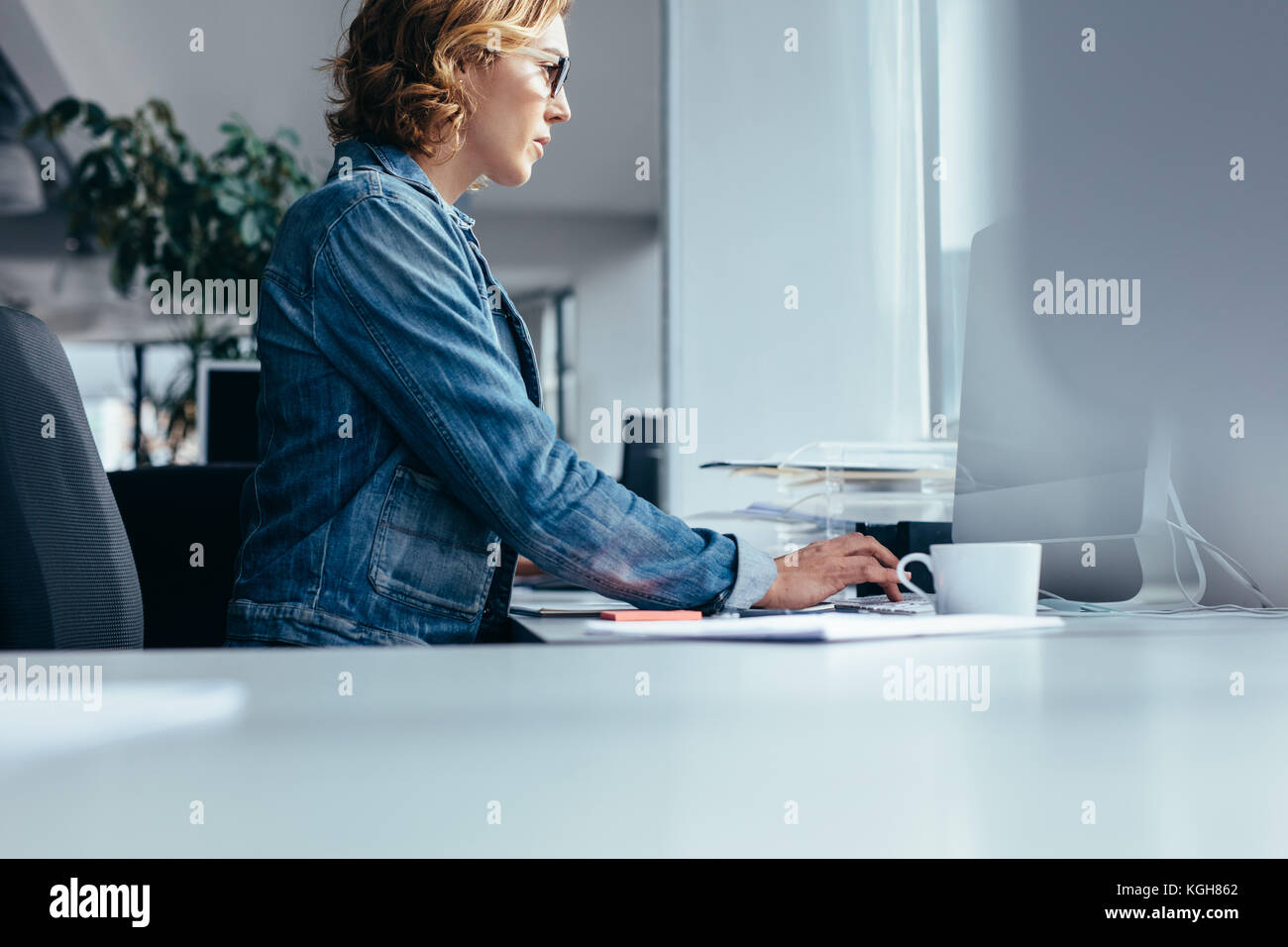 Side view of young businesswoman working in office. Female designer ...