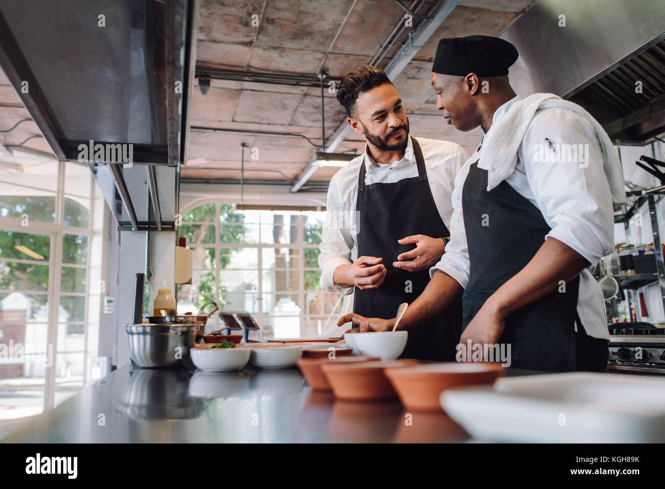 Two male cooks preparing food on restaurant kitchen. Chefs talking ...