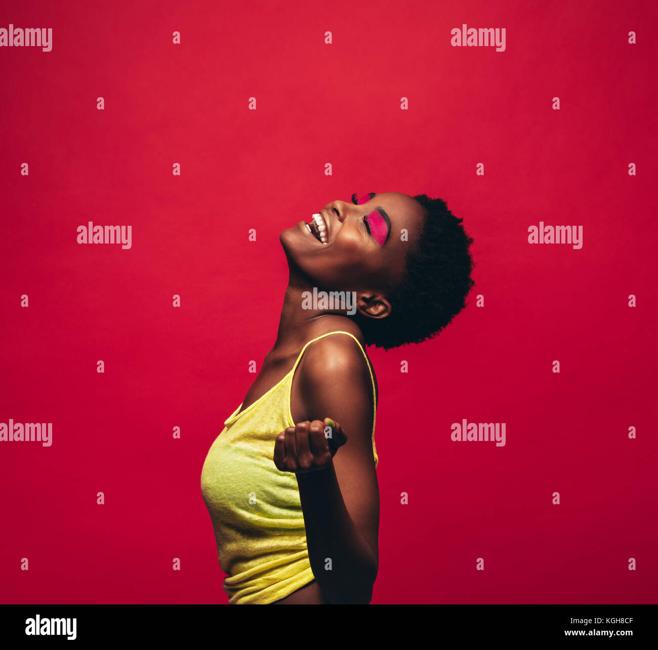 Cheerful young woman dancing over red background. African female model ...