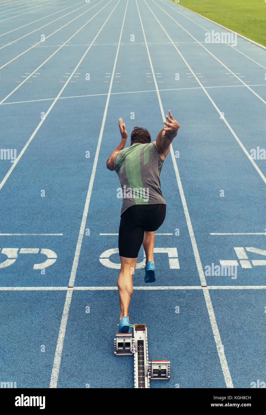 Rear view of an athlete starting his sprint on an all-weather running ...