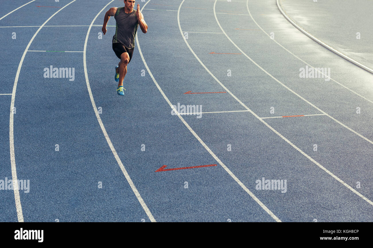 Athlete running on an all-weather running track alone. Runner sprinting ...