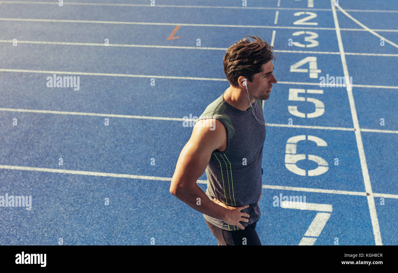 Athlete standing on a running track near the start line. Runner wearing ...