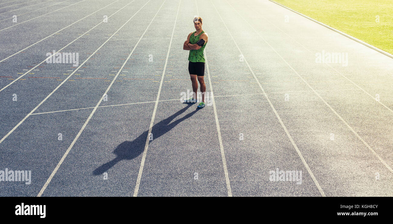 Runner standing on running track with hands folded. Athlete wearing ...