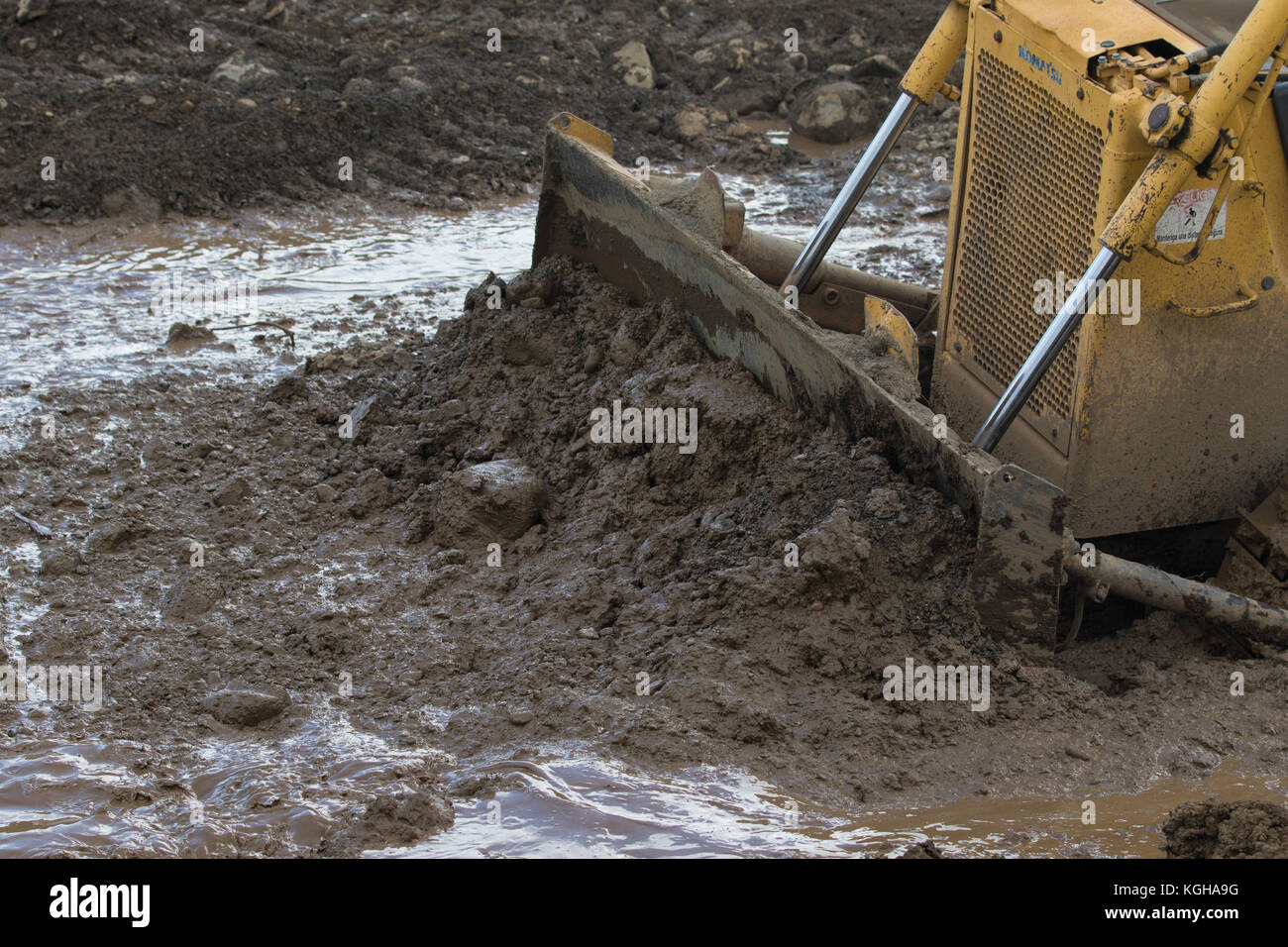 Earthmoving equipment removes muck and levels the ground during an ...