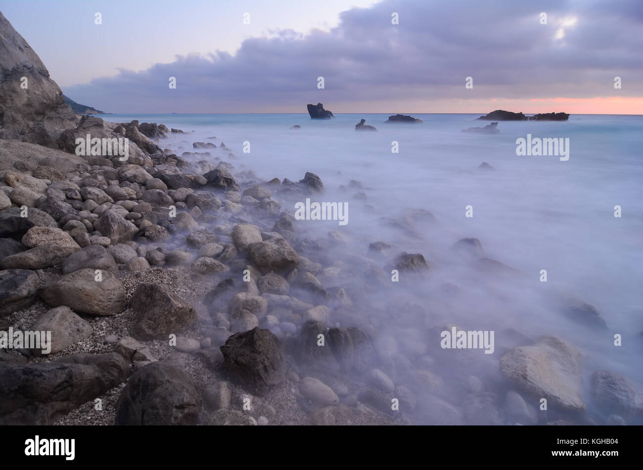 Rocky coast immediately after sunset, stones in milky waves, undulating ...