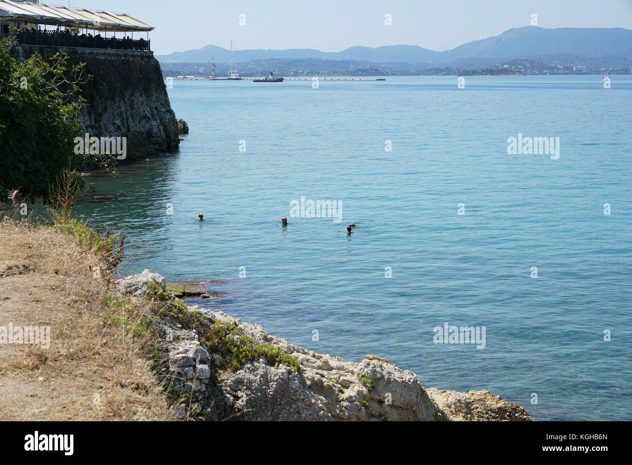 Corfu, Greece: People swimming in the sea at the beach of Kerkyra Old ...