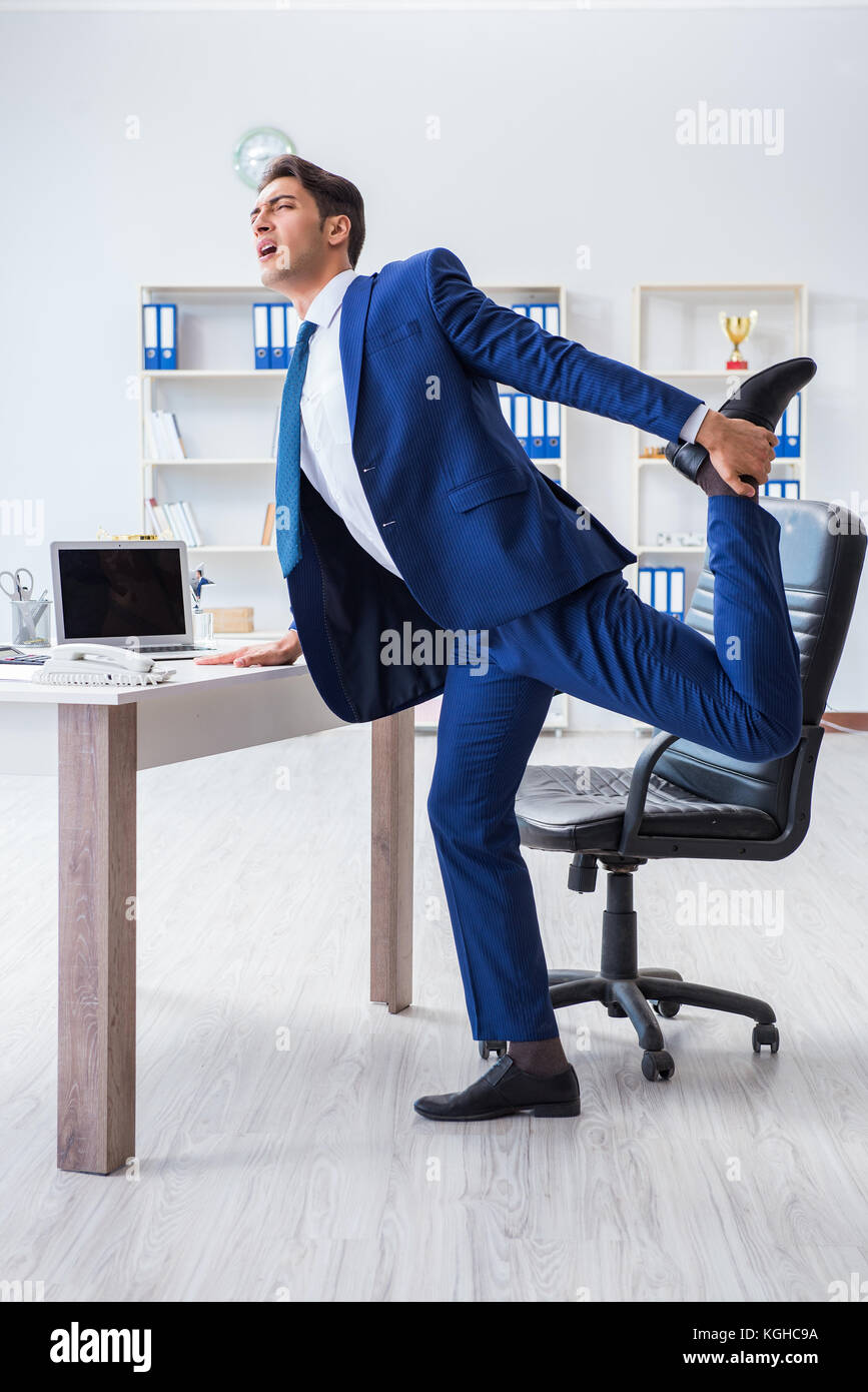 Young businessman doing sports stretching at workplace Stock Photo - Alamy