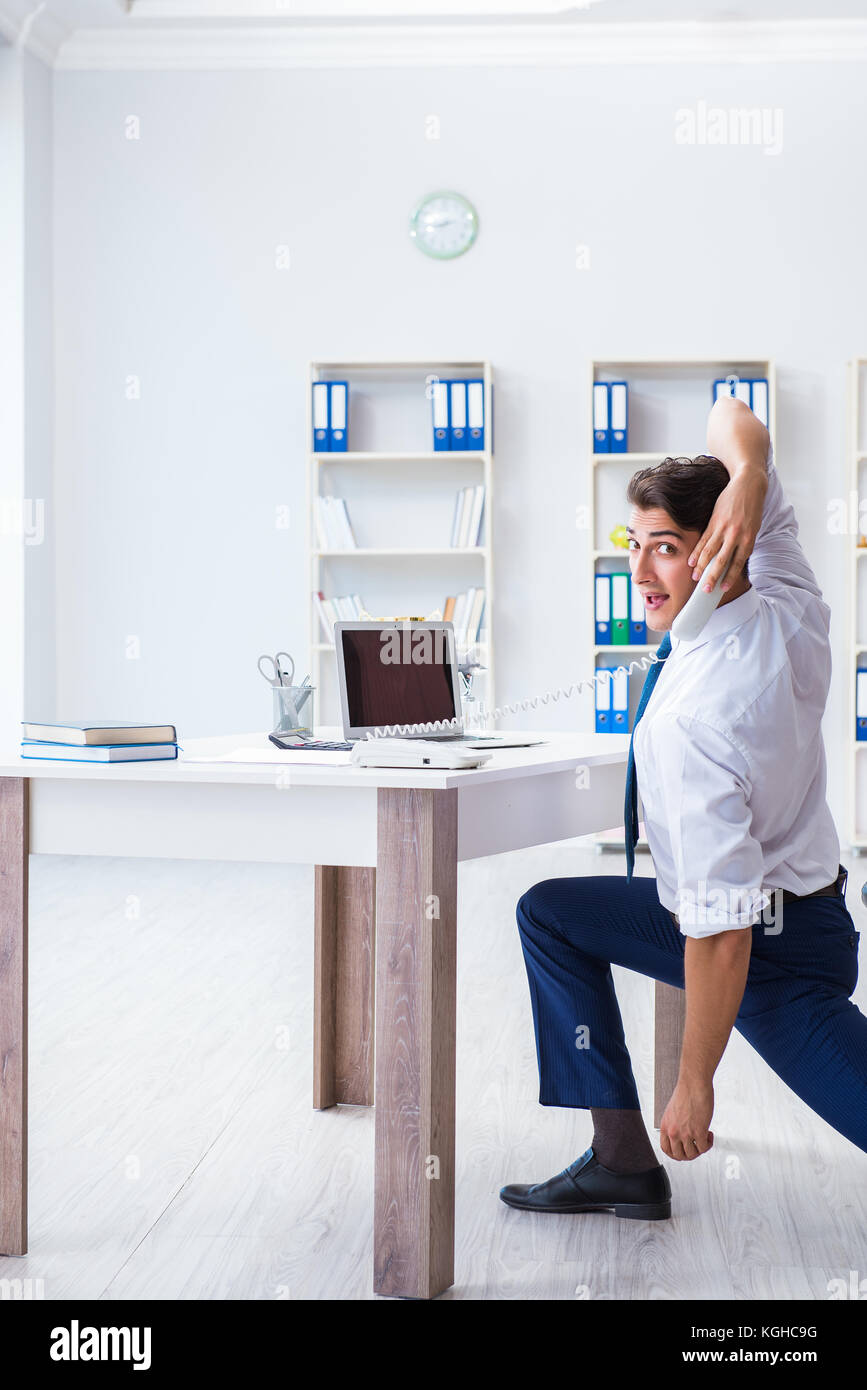 Young businessman doing sports stretching at workplace Stock Photo - Alamy